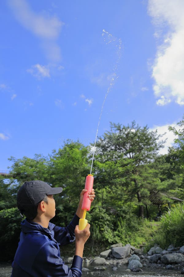 Japanese Junior High School Student Playing in the River with Water Gun ...