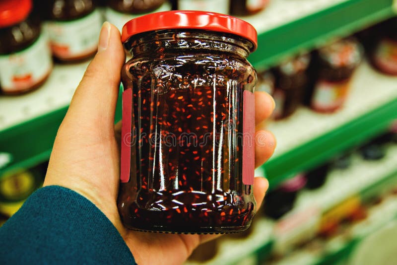 Jar of Raspberry Jam in the Hands of the Buyer in the Hypermarket Stock ...