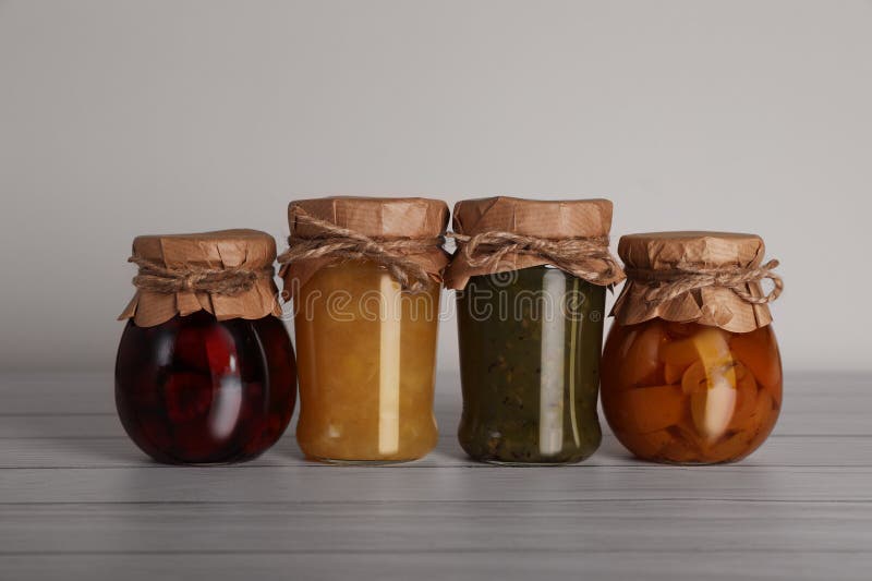 Jars with Preserved Fruit Jams on White Wooden Table Stock Photo ...