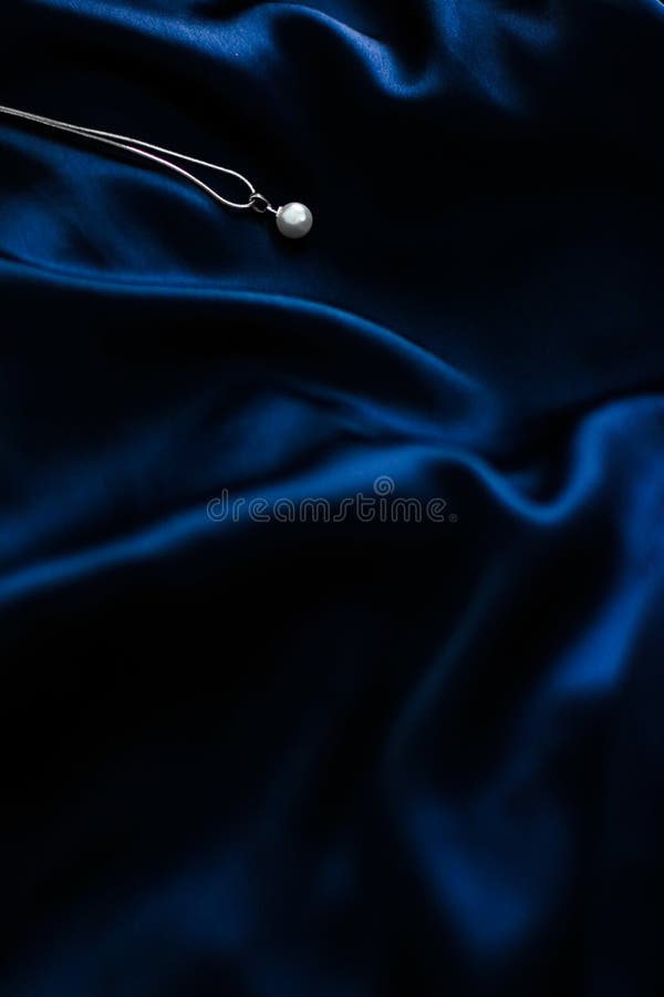 Luxury White Gold Pearl Necklace On Dark Blue Silk Background Holiday
