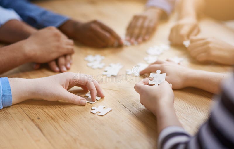 Jigsaw Solutions. Shot of a Group of People Building a Puzzle Together ...