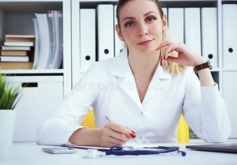 Jonge Vrouwelijke Artsenzitting Bij De Lijst En Het Werken Op Het