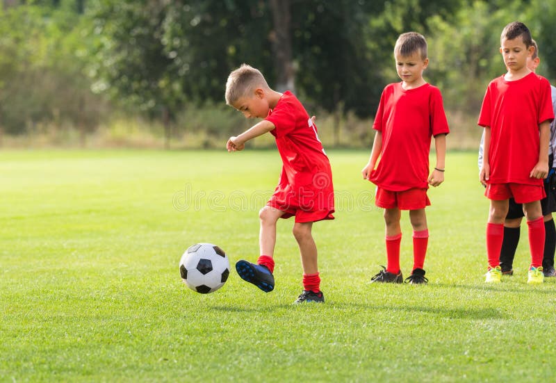 Jongen Het Schoppen Voetbal Door Knie Op Grijs Wordt Geïsoleerd Stock ...