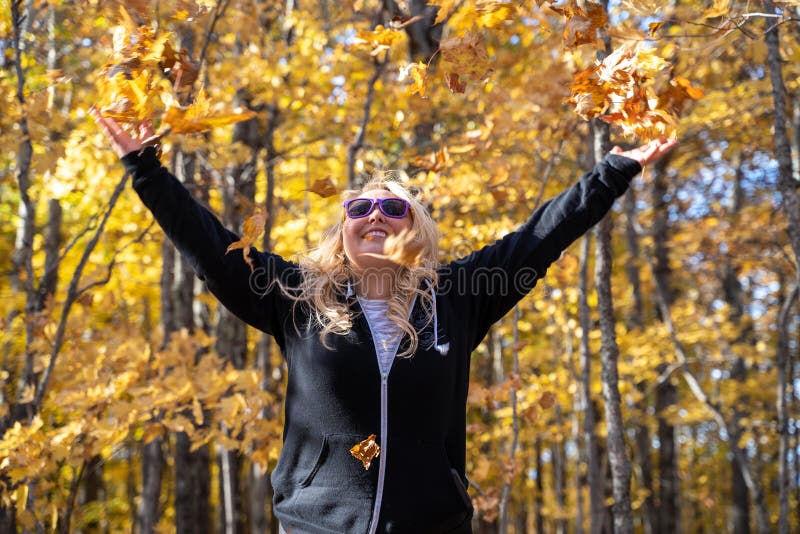 Joyful Blond Woman Throws Fall Leaves in the Air in a Forest Stock ...