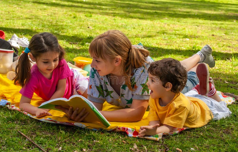 Joyful Family in the Park on the Grass Reading a Book Stock Photo ...