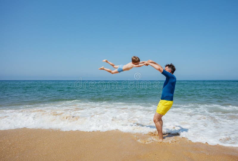 Joyful Father Spins Son Around As Waves Crash on a Sunny Beach Stock ... Joyful Father Spins Son Around As Waves Crash on a Sunny Beach Stock ...