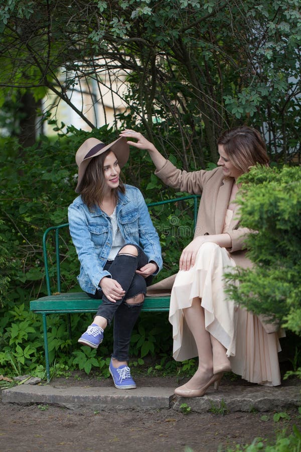 Joyful Friends Talking and Sitting on a Park Bench Outdoors Stock Photo ...