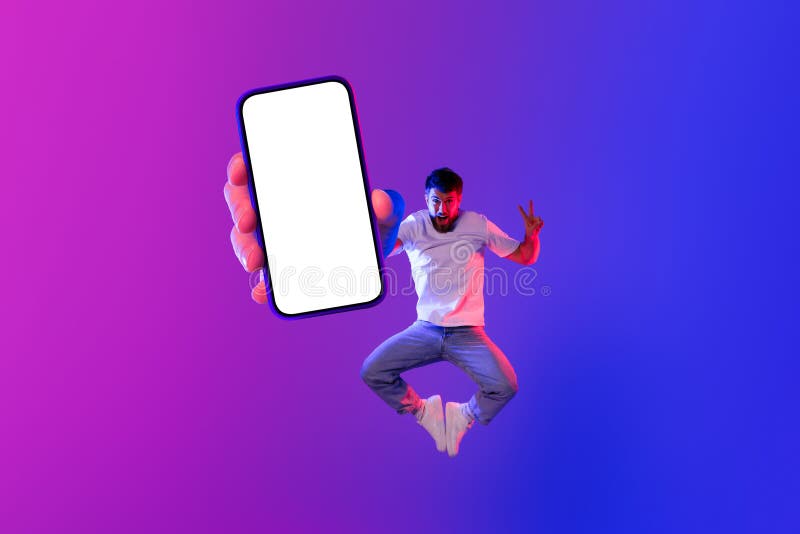 Joyful Guy Holding Big Smartphone Empty Screen Jumping in Studio Stock ...