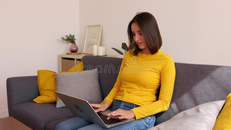 Joyful Millennial Female Using Laptop Computer Sitting on Couch at ...