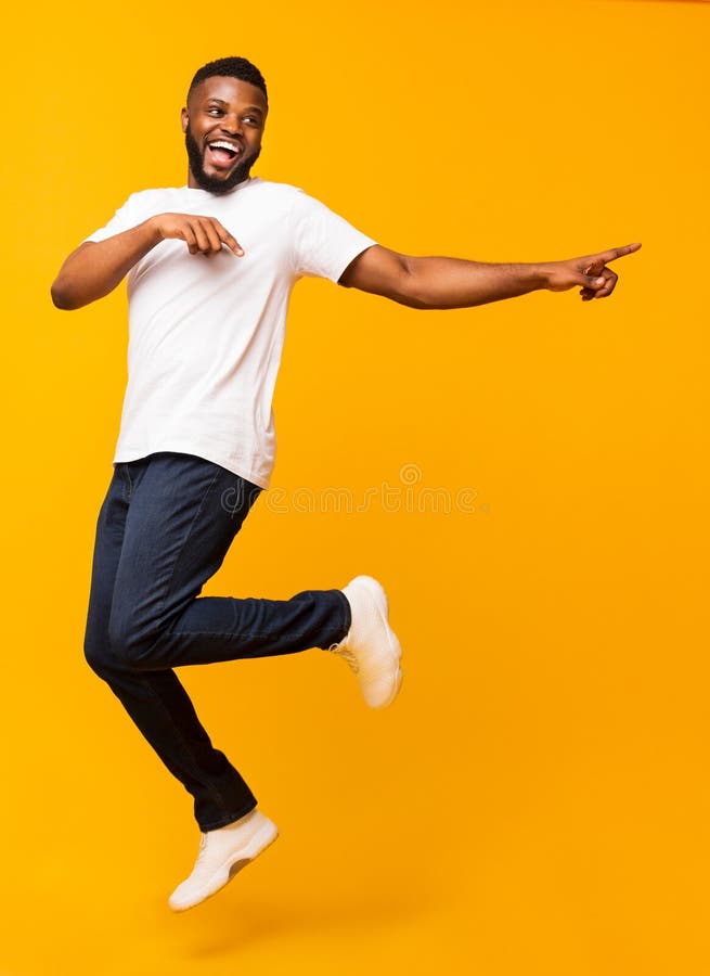 Joyful Millennial Guy Jumping on Air and Pointing Aside Stock Image ...