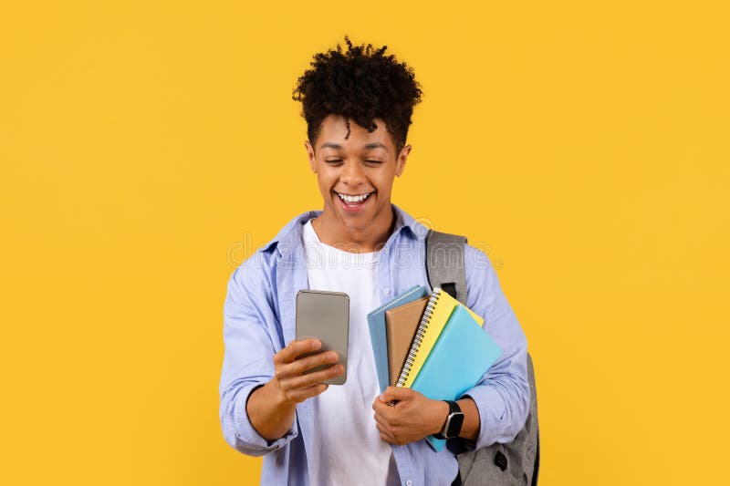 Joyful Student Using Smartphone with Notebooks on Yellow Stock Photo ...