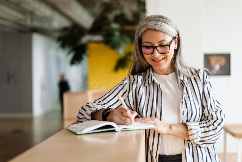 Joyful White-haired Mature Woman Smiling while Writing Down Notes Stock ...