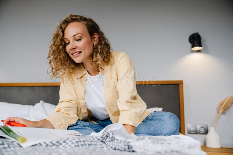 Joyful Woman Studying with Exercise Book while Sitting in Bed at Home ...