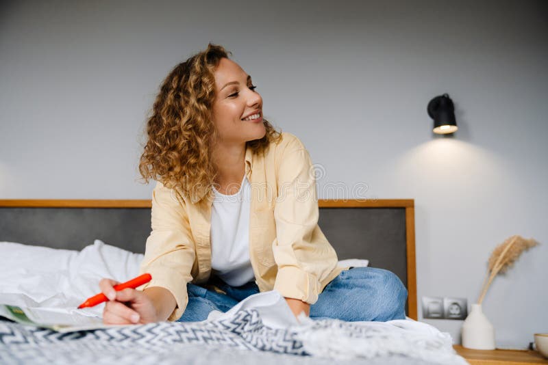 Joyful Woman Studying with Exercise Book while Sitting in Bed at Home ...