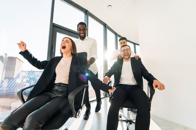 Joyful Work Colleagues Ride Chairs Around the Office. Stock Photo ...