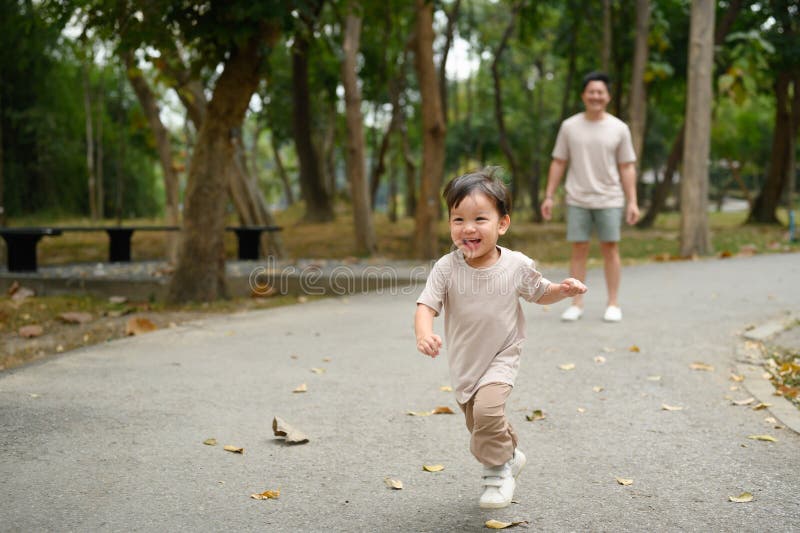 Joyful Young Child Running Along a Park Pathway with His Father Stock ...