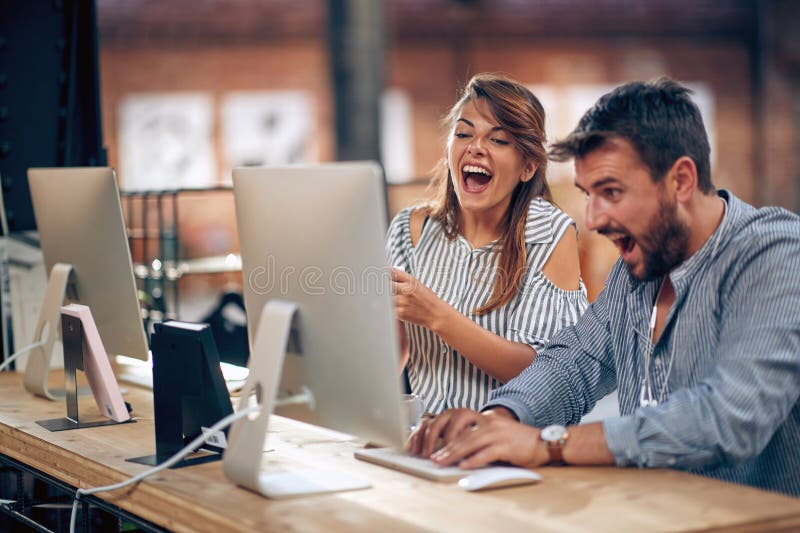 Joyful Young Colleagues Working and Looking at Computer Screen Together ...