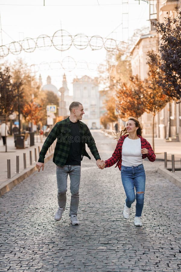 Joyful Young Couple Walking Hand in Hand through a Charming Cobblestone ...