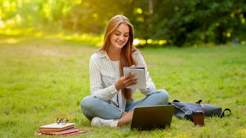 Joyful Young Student Girl Sitting on Lawn with Notepad and Taking Notes ...