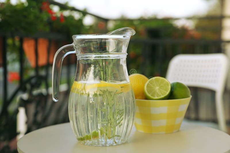 Jug with Refreshing Lemon Water and Citrus Fruits in Bowl on Light ...