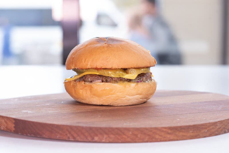 Juicy Cheeseburger on a Wooden Plate on a Table in a Restaurant. Stock ...