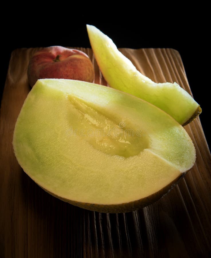 Juicy Mellow Melon and Peach on the Wooden Desk on the Black Background ...
