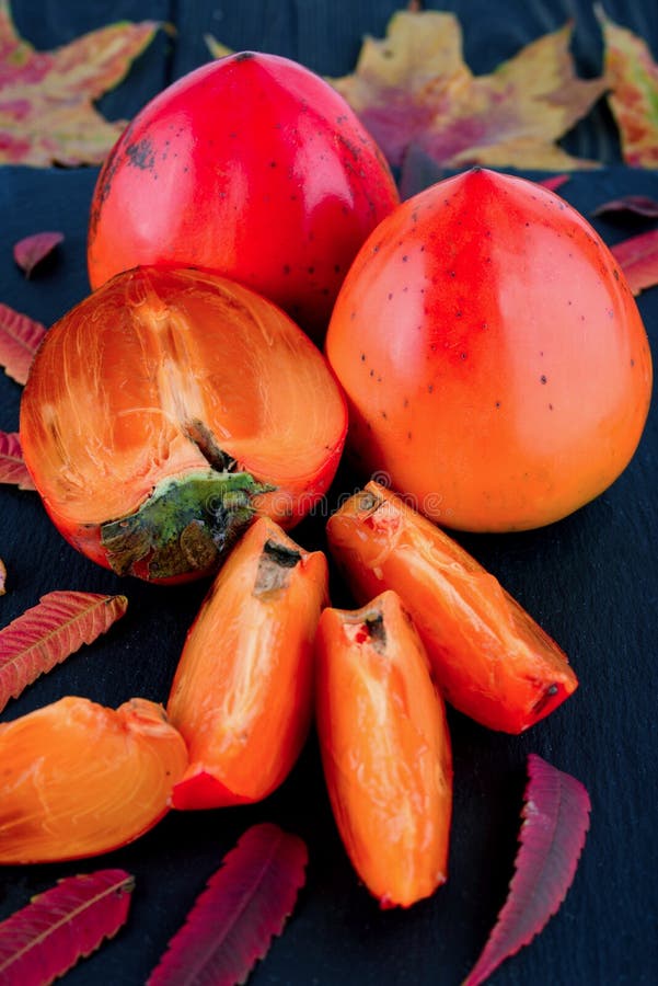 Juicy Munch among the Autumn Leaves. Persimmon in a Clay Plate. Stock ...
