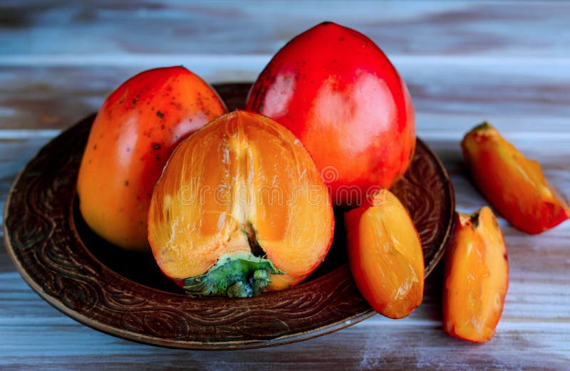 Juicy Munch among the Autumn Leaves. Persimmon in a Clay Plate. Stock ...