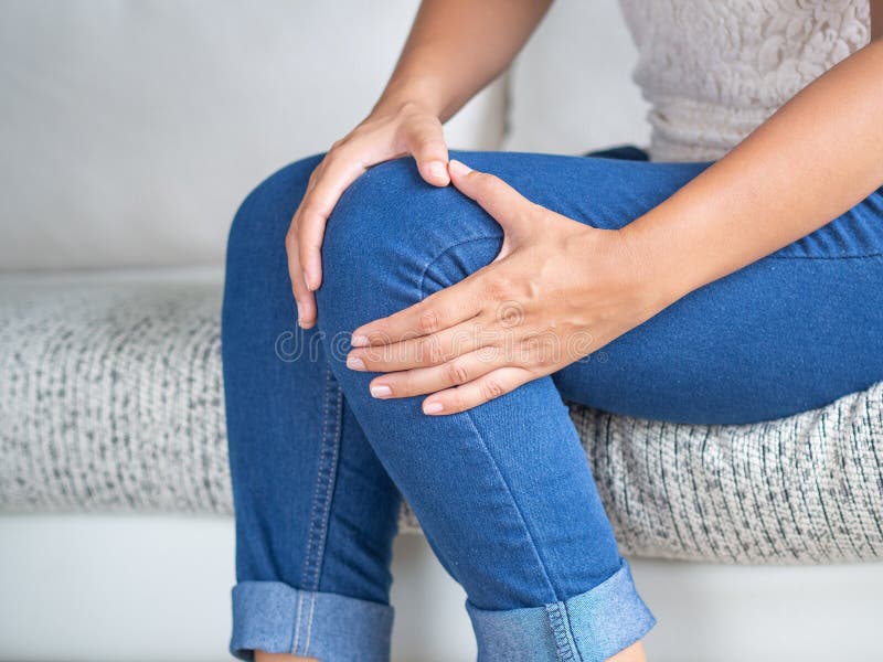 Junge Frau Der Nahaufnahme, Die Auf Sofa Und Glaubendem Knie Sitzt Zu ... Junge Frau Der Nahaufnahme, Die Auf Sofa Und Glaubendem Knie Sitzt Zu ...