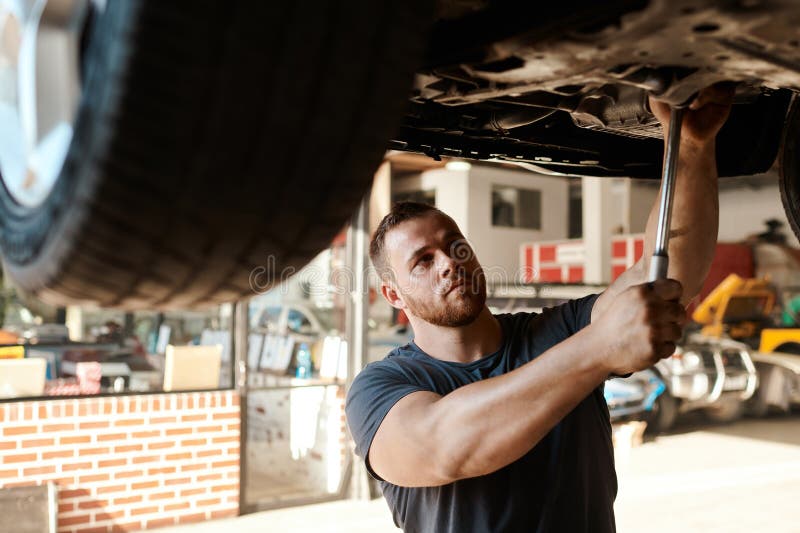 Just Another Day at the Workshop. a Mechanic Working Under a Lifted Car ...
