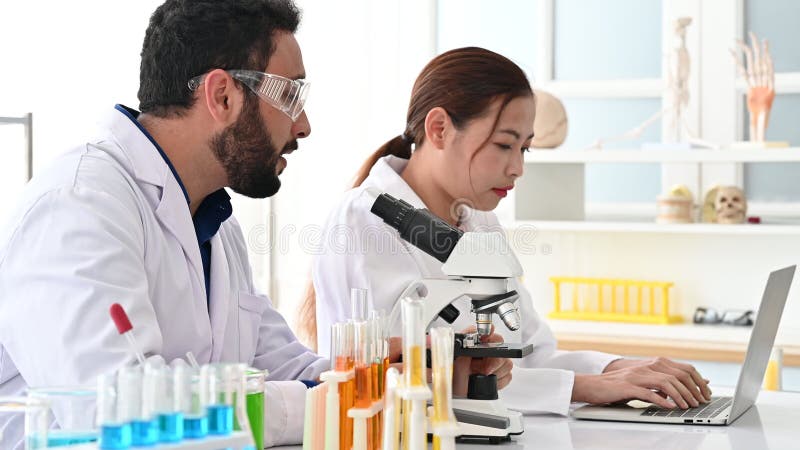 4K Scientists and Laboratory Workers Sitting at Table and Looks into ...