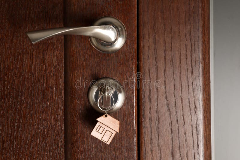 Key with House-shaped Trinket in Door Lock, Closeup Stock Photo - Image ...