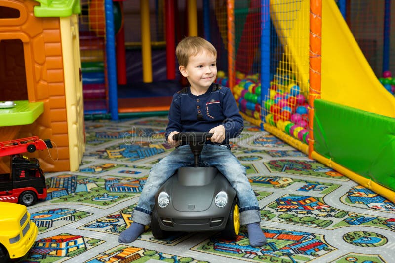 The Kid is Happy Driving a Car at Home in the Playroom. Stock Photo ...