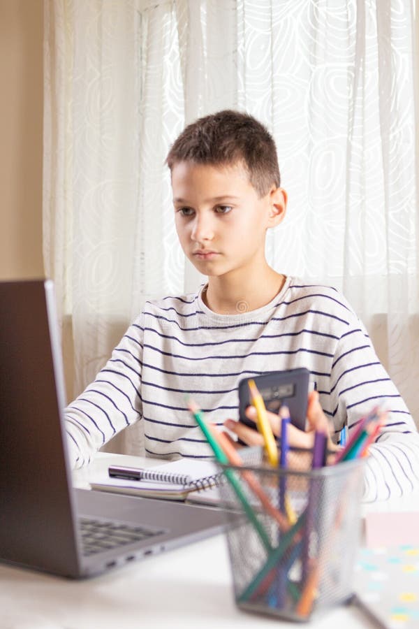 Kid Sitting with Laptop Computer and Scrolling Phone instead of Doing ...