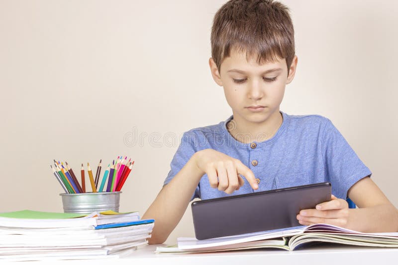 Kid Sitting at Table with Books Notebooks and Using Tablet Computer ...