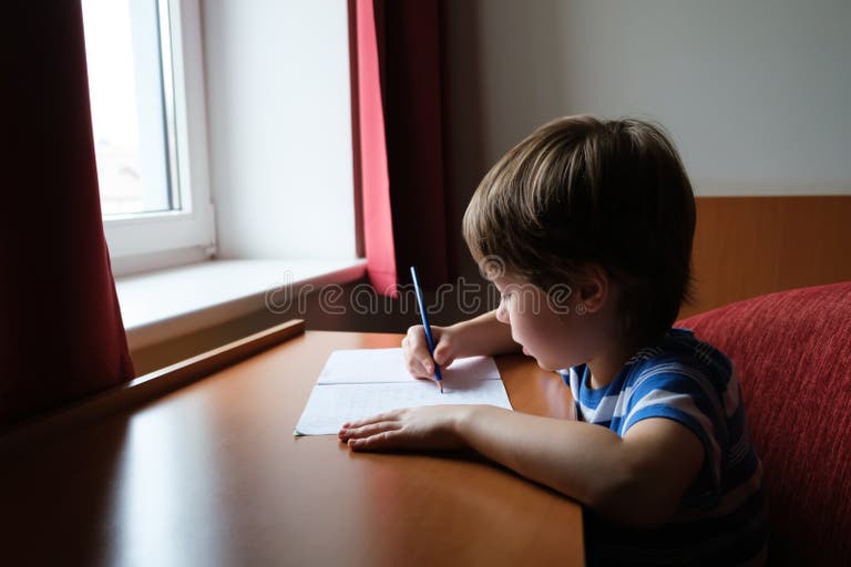 The Kid is Sitting at the Table and Doing Homework. the Child Writes ...