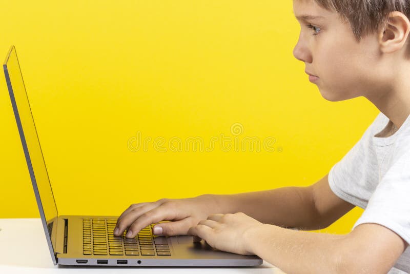 Kid Sitting at the Table and Using Laptop Computer, Yellow Background ...
