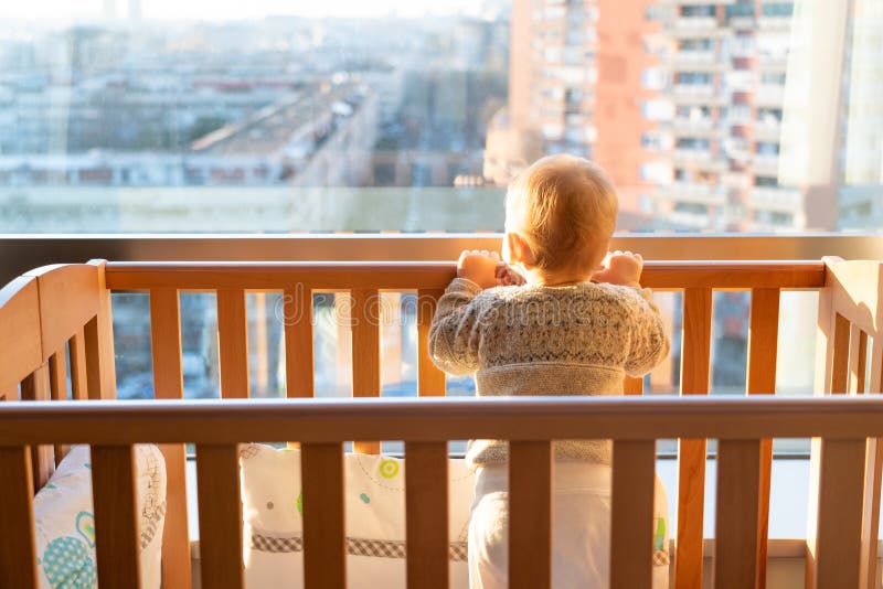 The Kid Stands in Front of the Window and Looks at the City from Above ...