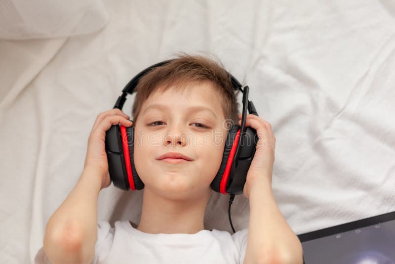 Kid Using Digital Tablet and Laptop Listening To Music on the Carpet at ...