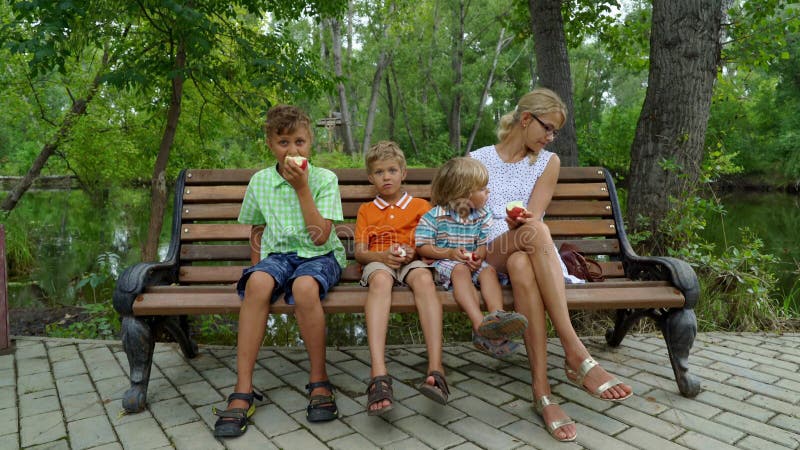 Kids with Mother Sitting on the Bench and Eating Apples Stock Video ...