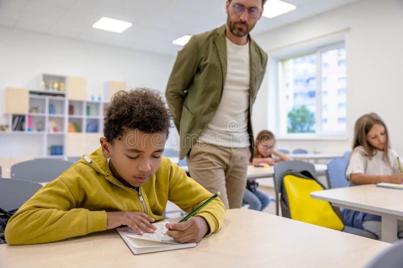 Kids Writing a Test and Teacher Contolling Them Stock Image - Image of ...