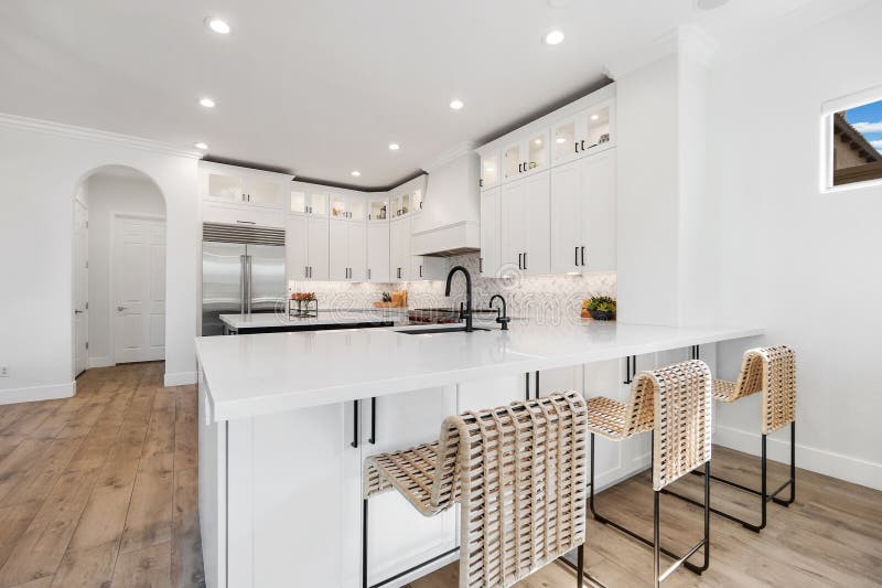 A Kitchen with White Cabinets, a Large Island, Stools, and Fridge Stock ...