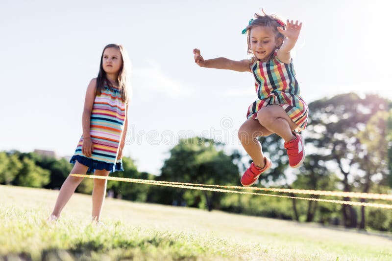 Kleines Mädchen in Einem Bunten Kleid, Das Durch Das Gummiband Springt ...