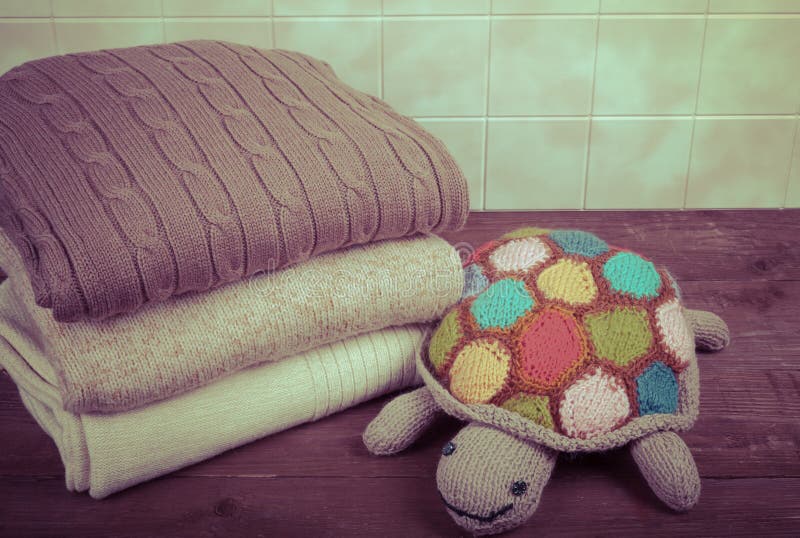 Knitted Toy Turtle with the Stack of Knitted Clothes on Wooden T Stock ...