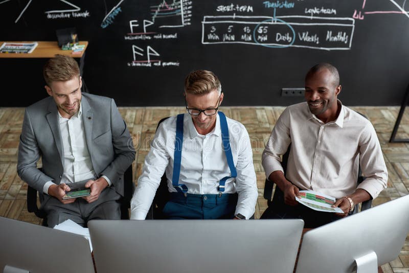 We Know, we Do. Cheerful Co-workers Traders Sitting Next To Each Other ...