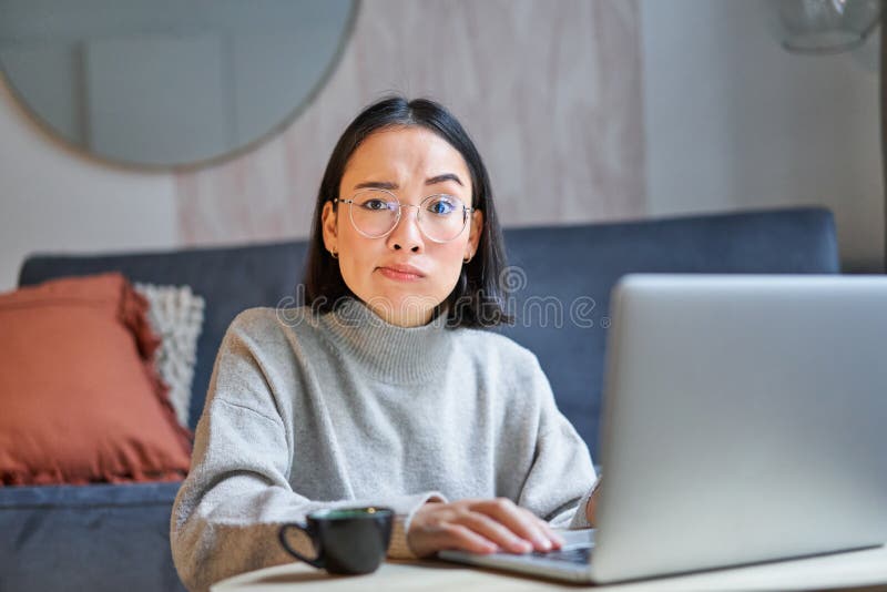 Korean Woman with Perplexed Face, Sitting with Laptop, Working on ...
