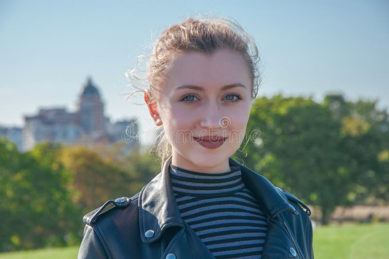La Belle Fille Blonde Se Tient Et Sourit Sur Le Fond Vert De Pelouse