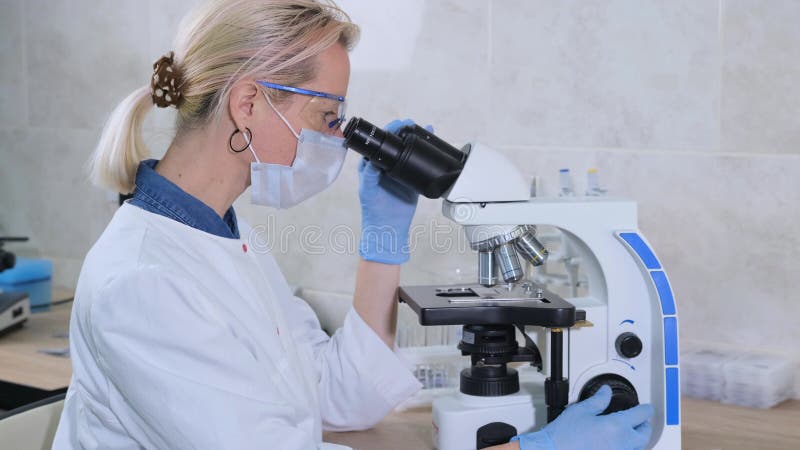A Laboratory Assistant Examines Samples Under a Microscope. Scientific Research in the ...