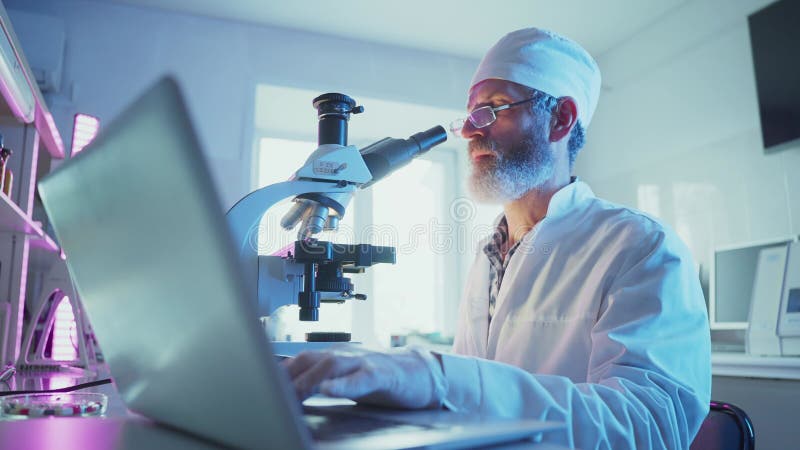 Scientist Analyzing Samples with Microscope and Laptop in Laboratory ...