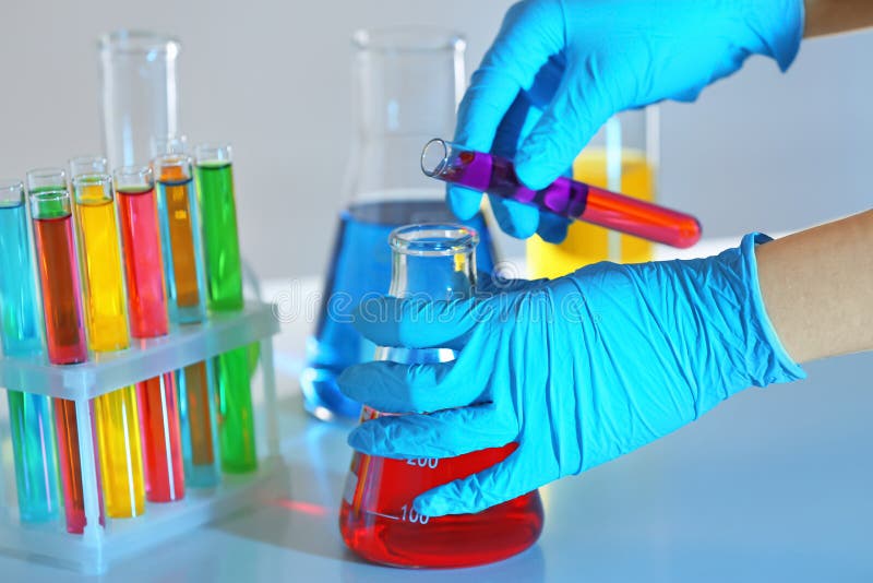 Laboratory Worker Pouring Liquid from Test Tube into Flask at Table ... Laboratory Worker Pouring Liquid from Test Tube into Flask at Table ...